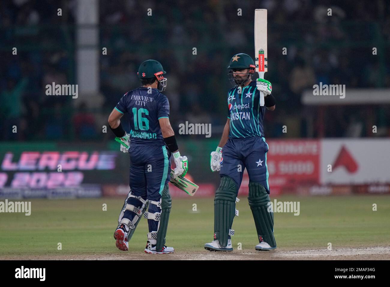 Pakistan's captain Babar Azam, right, raises his bat to celebrate ...