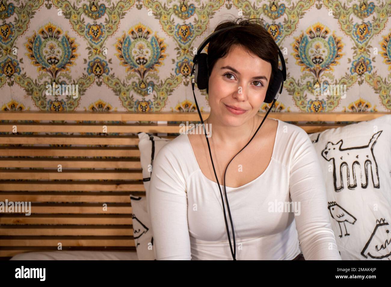 Belle femme écoute de la musique dans les écouteurs sur le lit. La ...