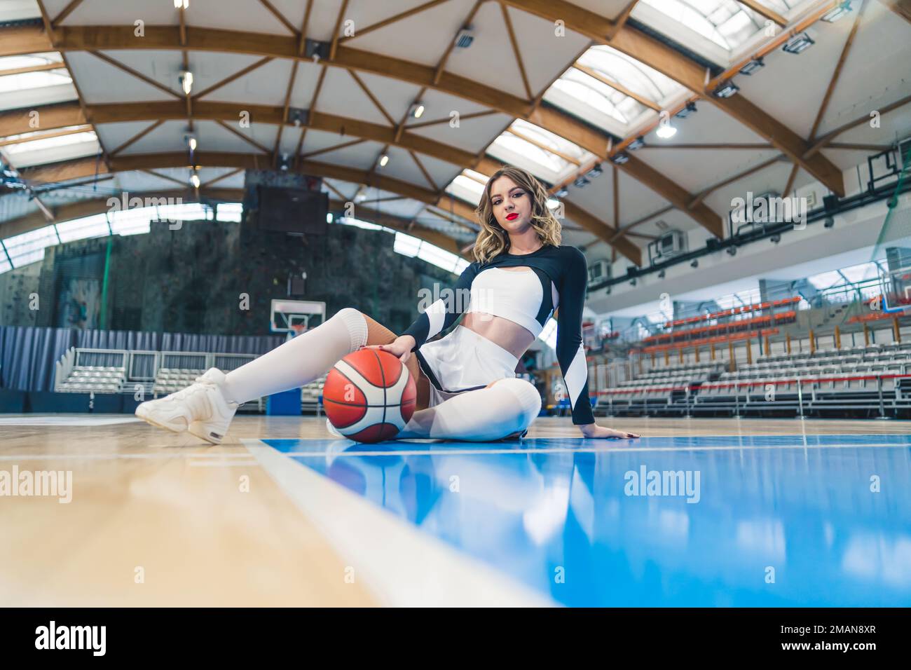 Vue de face d'une meneuse de gaieté posant avec un ballon de basket ...
