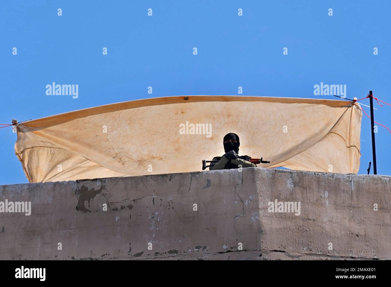 A Lebanese Hezbollah fighter holds his machine gun as he stands guard ...