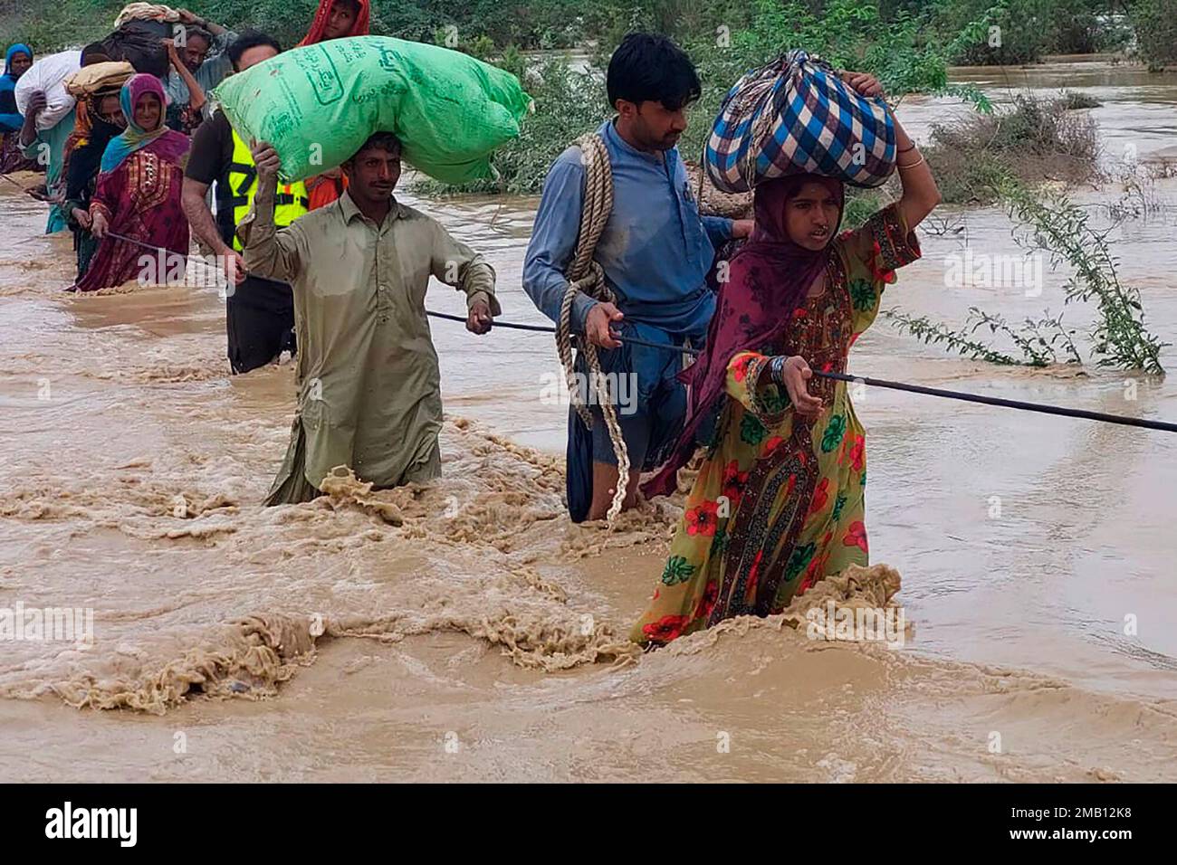 Villagers cross a flooded area to move into higher place after heavy ...