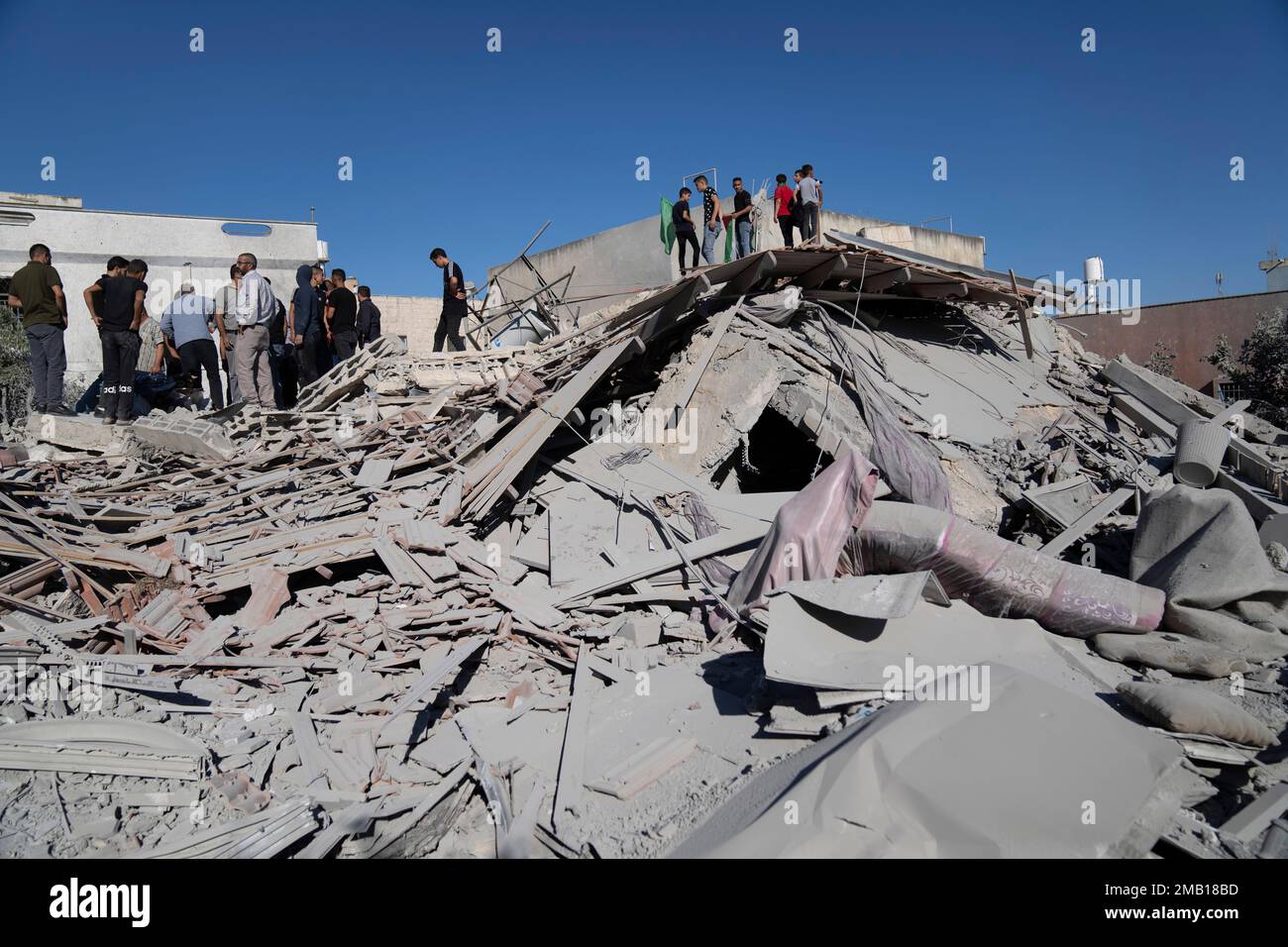 Palestinians gather on top of the rubble of the family house of Yahia ...