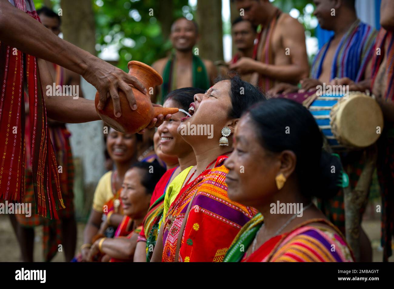 An Indian Rabha tribal Hindu priest serves traditional rice beer to the ...