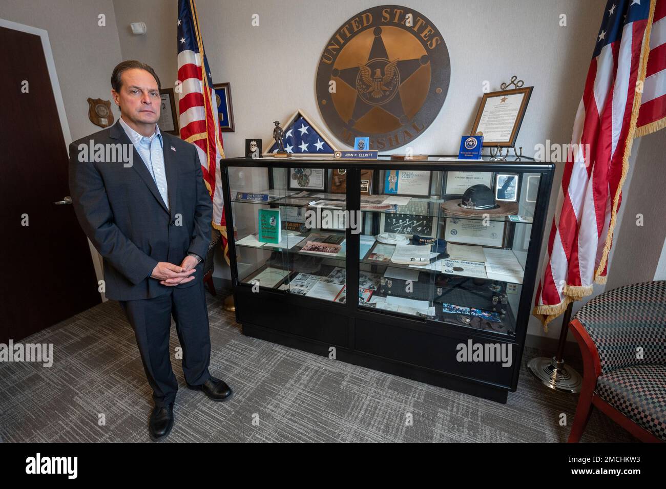 U.S. Marshal Peter J. Elliott poses for a photo with memorabilia of his ...