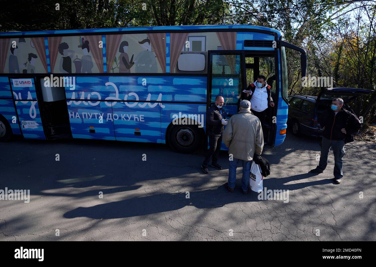 People wait by a bus being used as a mobile help center for the ...