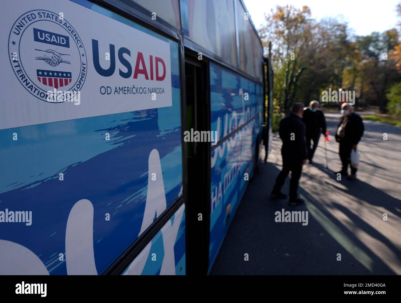 People wait by a bus being used as a mobile help center for the ...