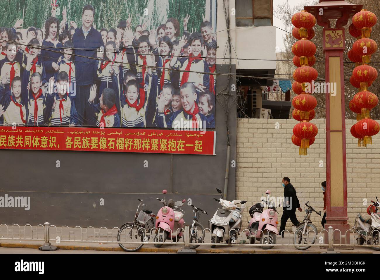 Residents walk past a propaganda board showing Chinese President Xi ...