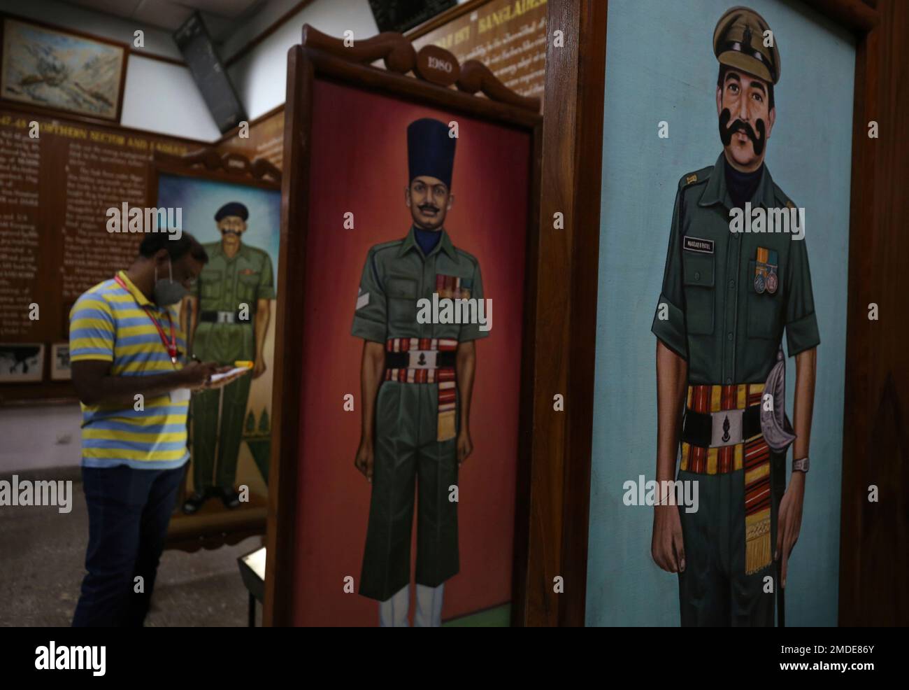 A journalist takes notes as he stands next to the murals of Indian army ...