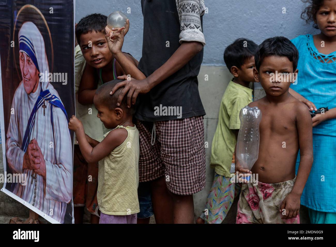 Impoverished people wait outside the Missionaries of Charity, the order ...