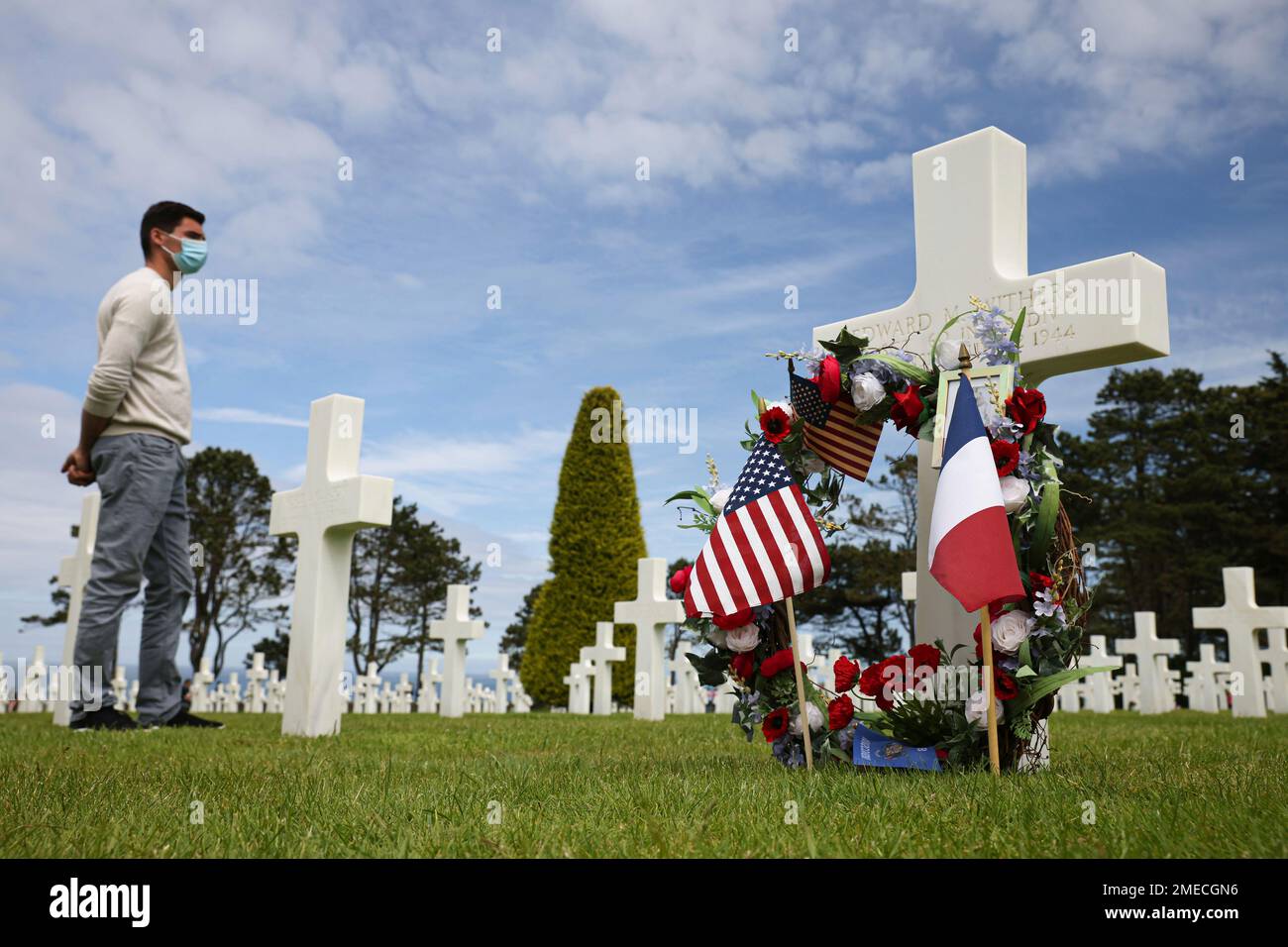 A man stands next to a headstone of a World War II soldier during a ...