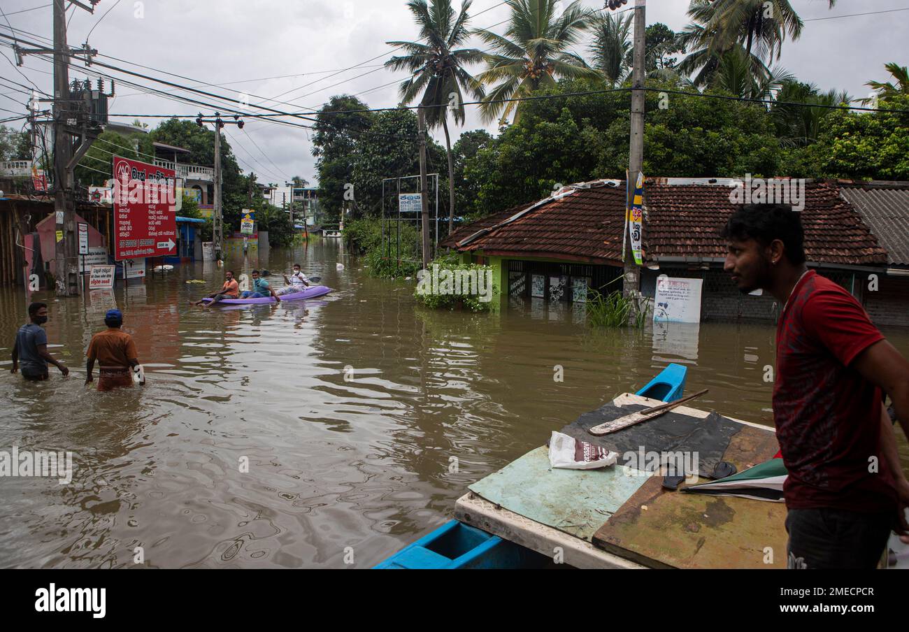 Sri Lankans stranded due to floods travel in a boat in an inundated ...