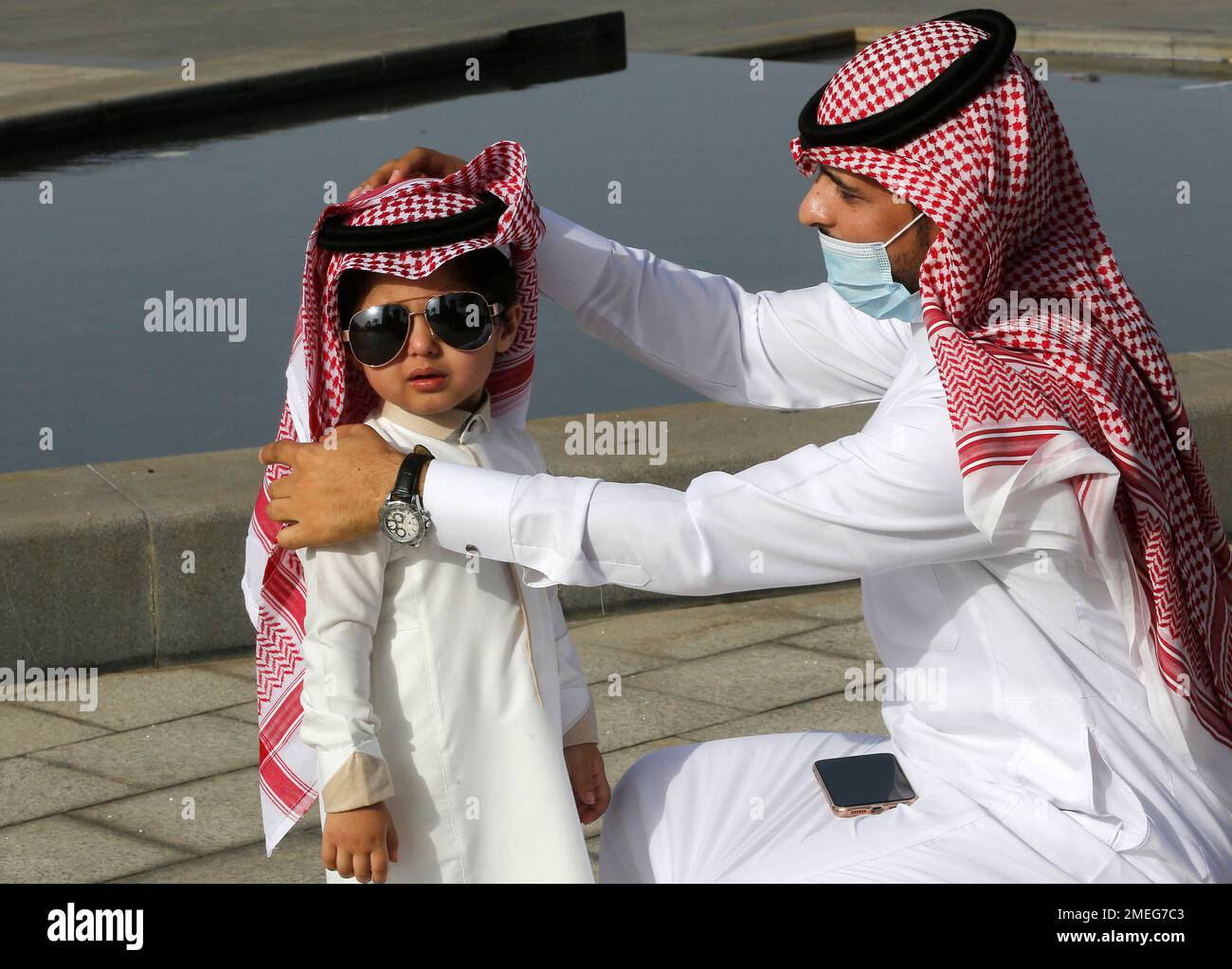 A Saudi man arranges his son's traditional "Ghutra", or head cover ...