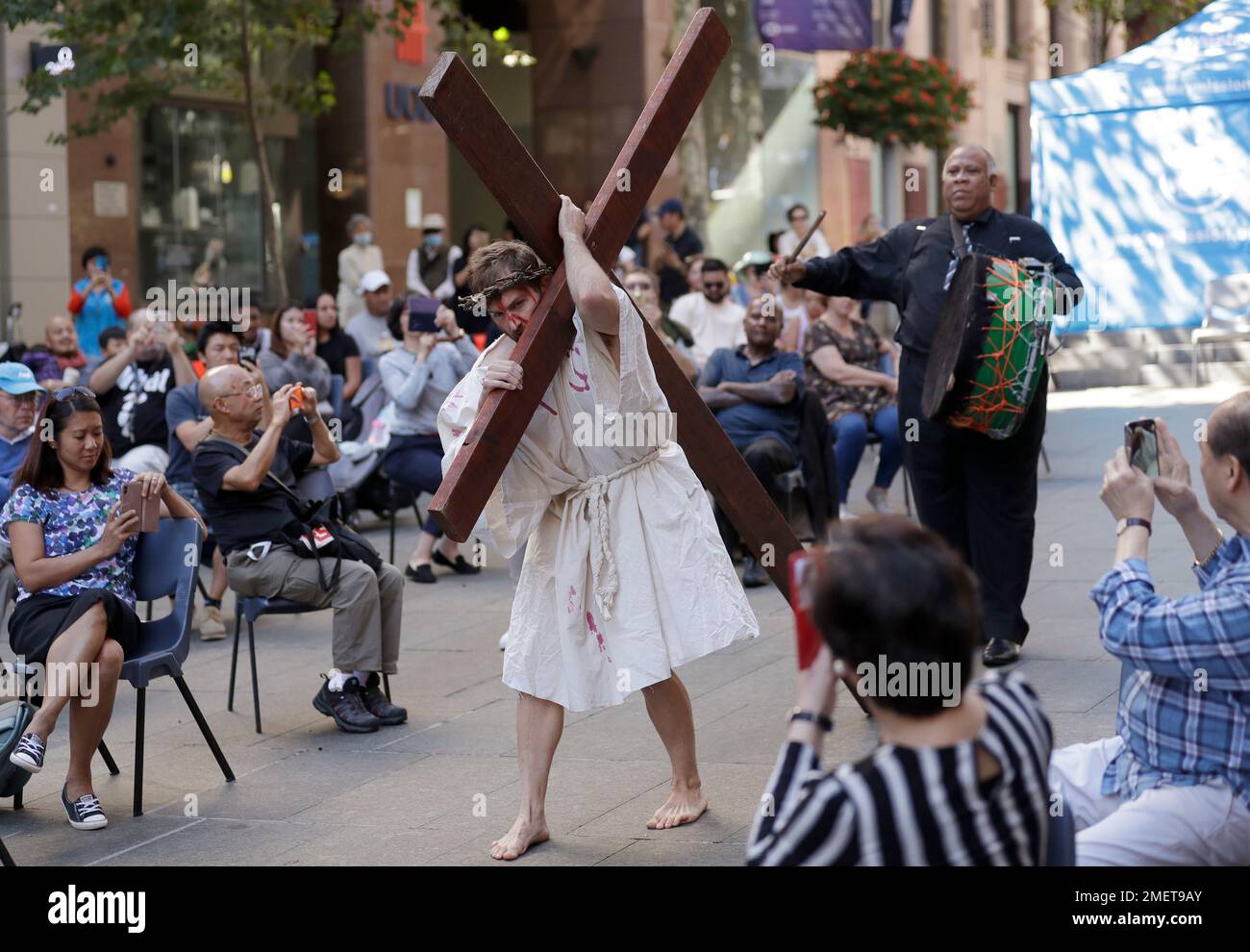 Actor Timothy Watkins carries a cross during his portrayal of Jesus ...