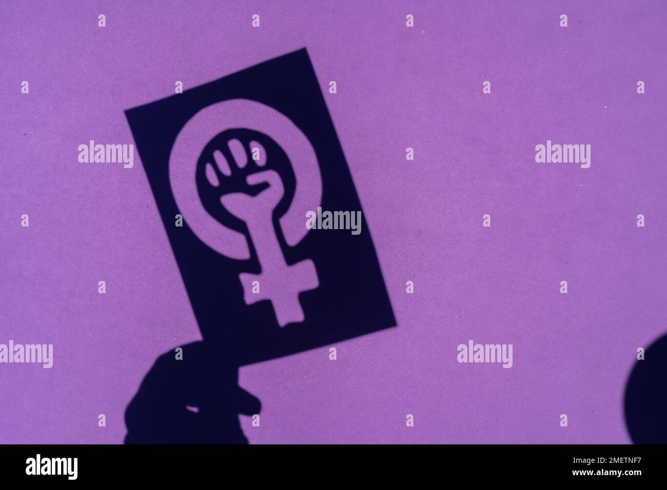 Ombre du symbole de la lutte pour le féminisme sur fond violet, poing ...
