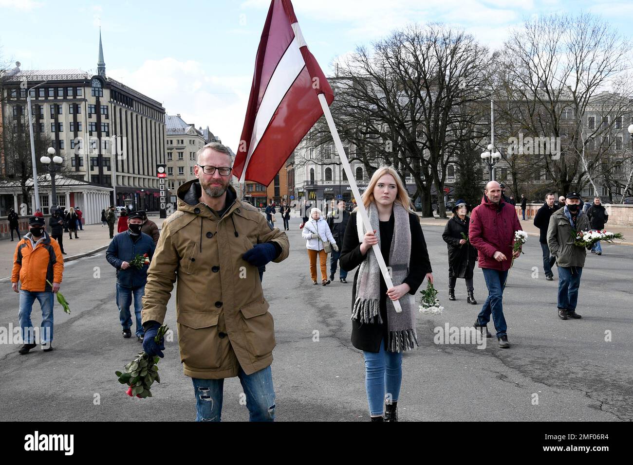 People, a woman holds a Latvian national flag, walk to lay flowers at ...