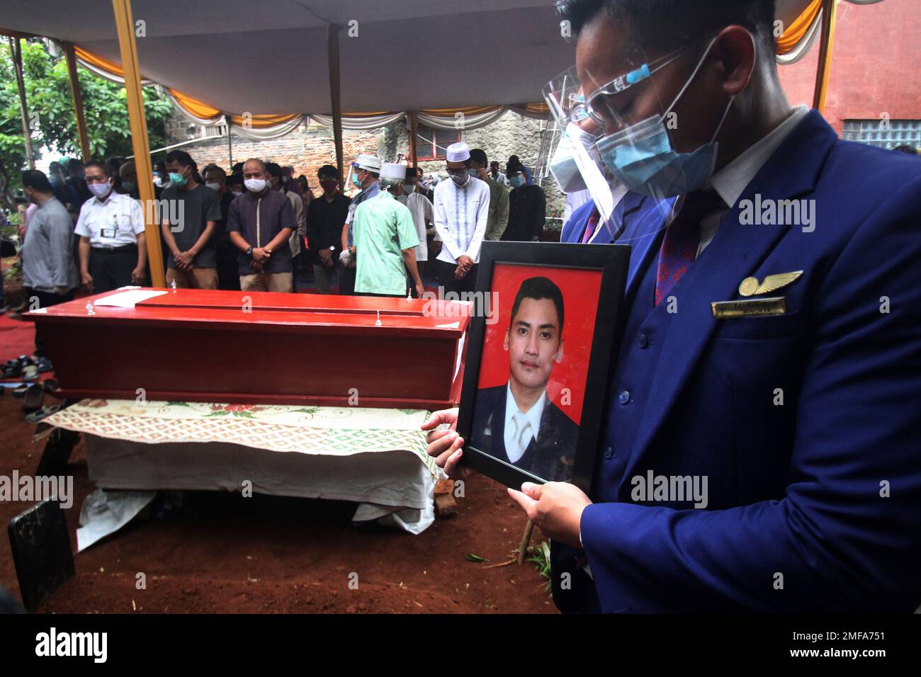 A colleague holds a portrait of Okky Bisma, a flight steward, one of ...