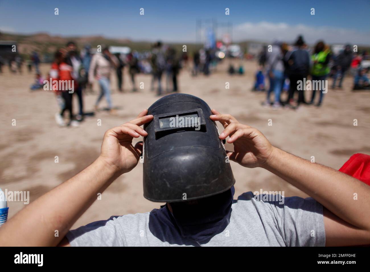 Using a welder's mask as protection, a man views a total eclipse in ...