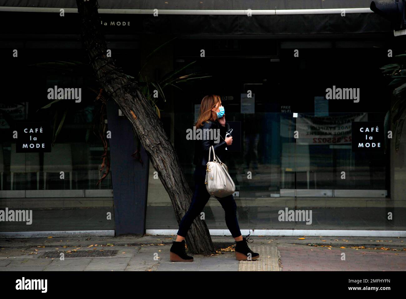 A woman wearing face mask walks at a main shopping street in capital ...