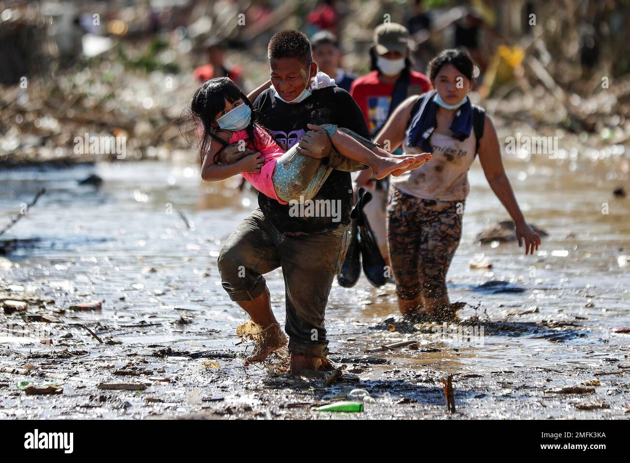 A man carries a girl through debris and floods in the typhoon-damaged ...
