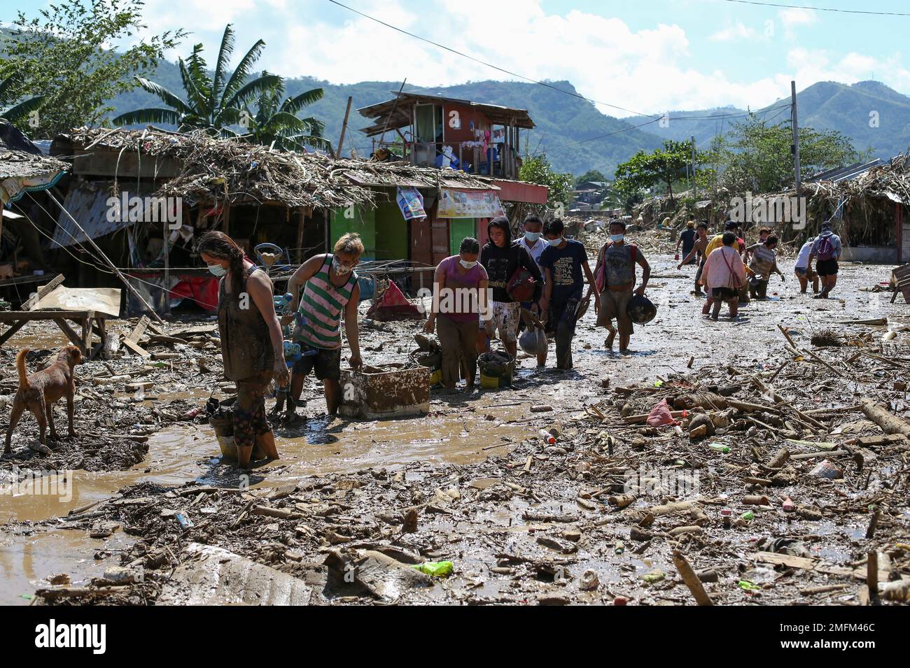 Residents walk through mud and debris as they return to retrieve ...