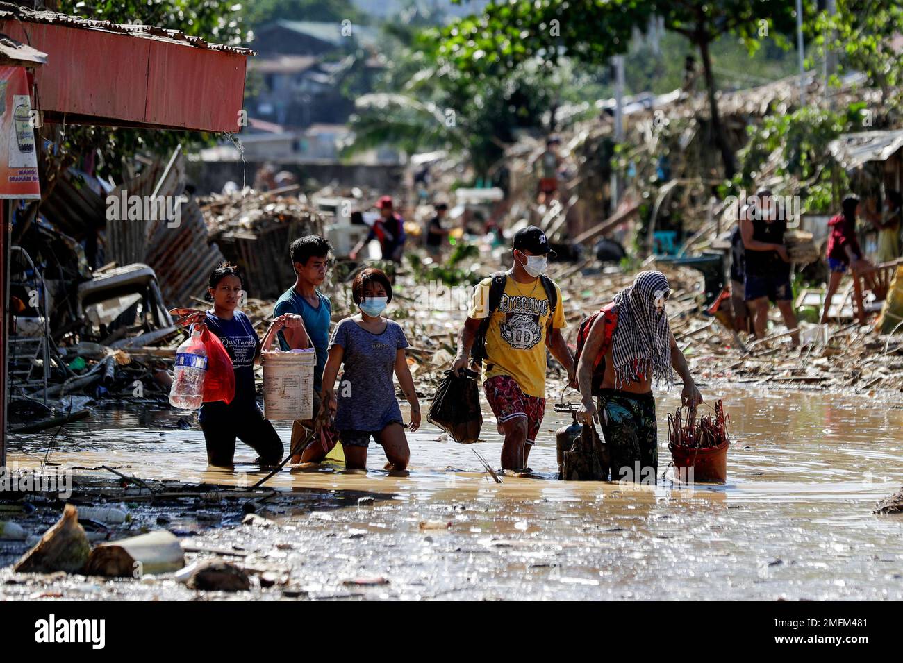 Residents walk on mud and debris as they retrieve belongings from their ...