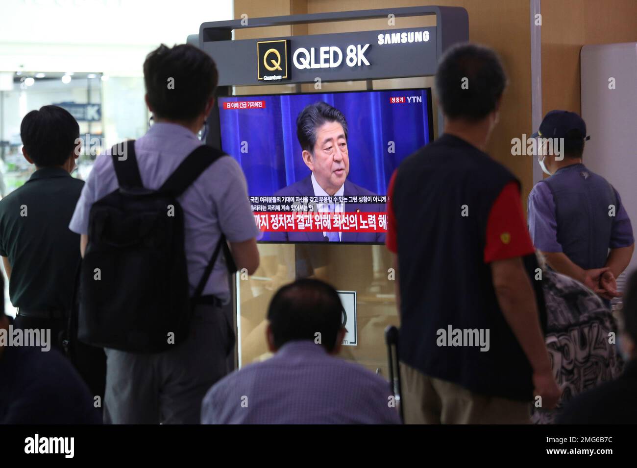 People watch a TV screen showing a live broadcast of Japan's Prime ...