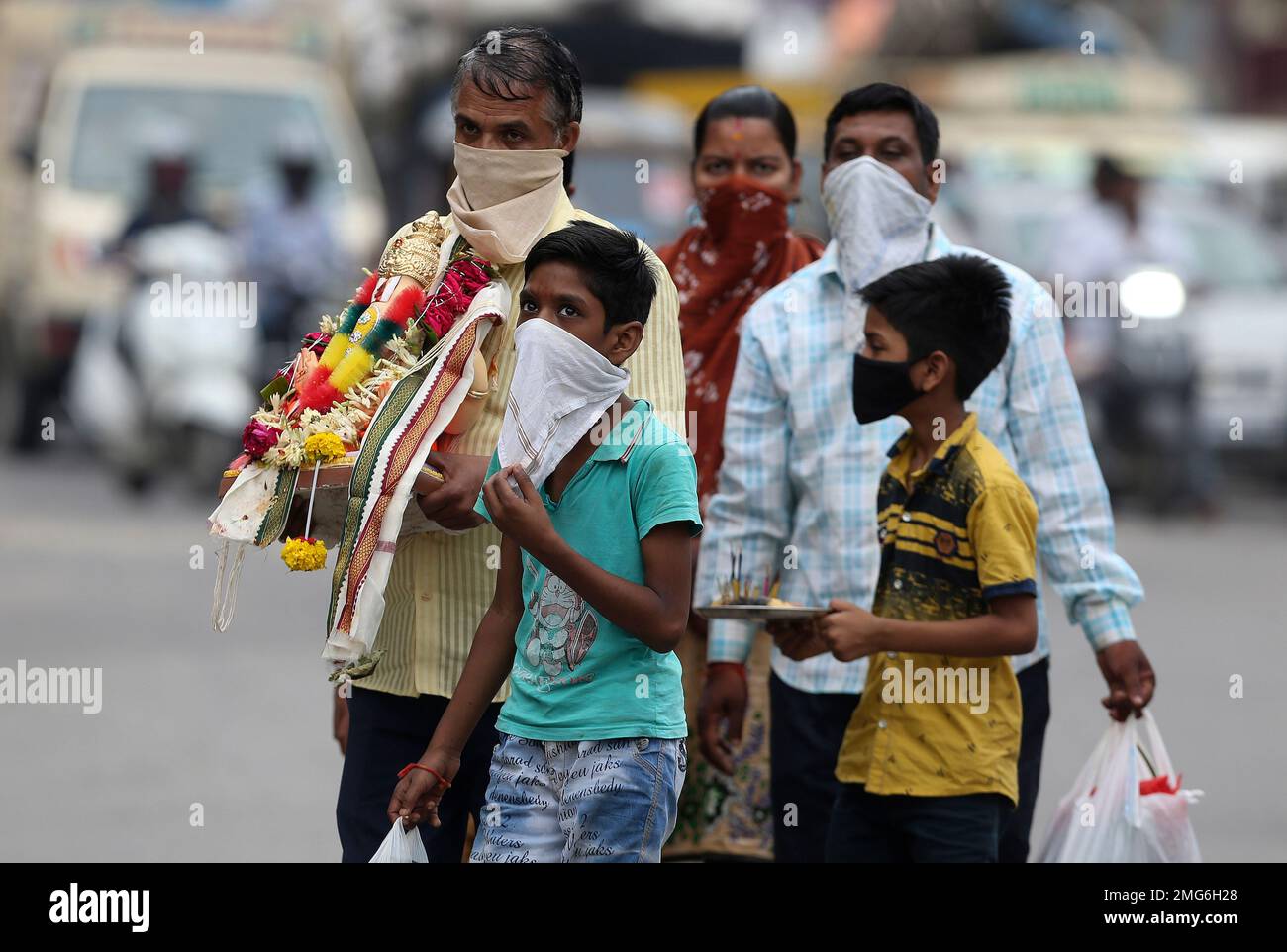 Members of a Hindu family wear face masks and carry an idol of elephant ...