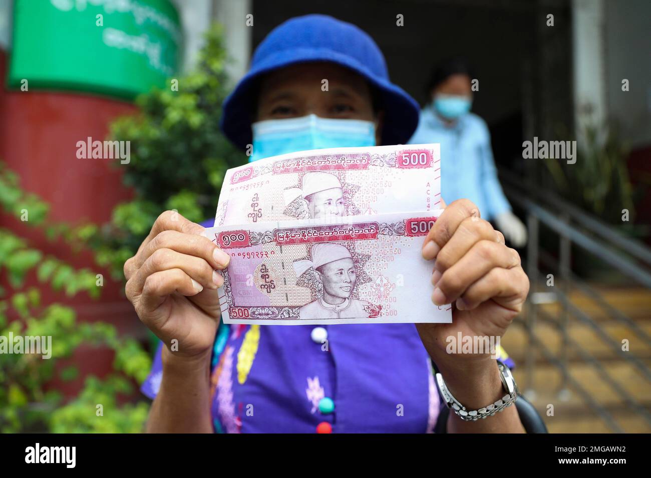 A woman shows new currency notes with the portrait of Gen. Aung San ...