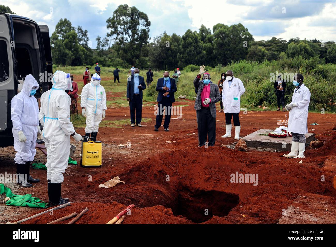 A priest prays over the grave of Stephen Ndungu Gitau, who died from ...