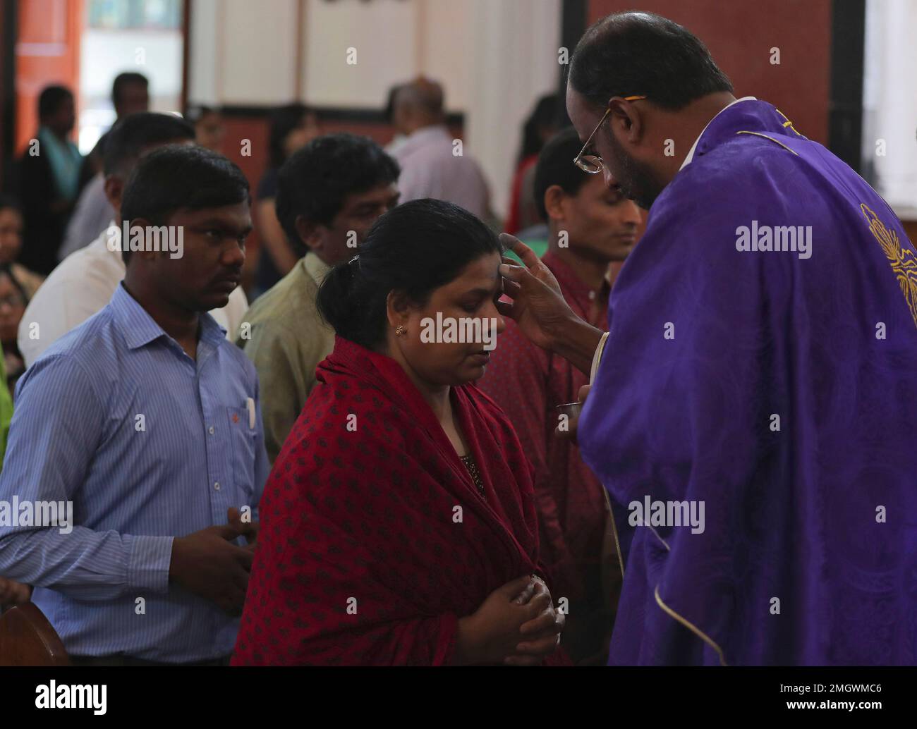 A Catholic priest marks the forehead of a devotee with the symbol of a ...