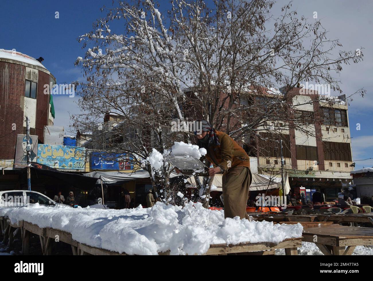 A vendor removes snow from his stall after heavy snowfall in Quetta ...
