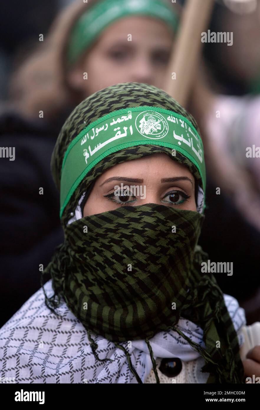 A Palestinian woman wears a headband with Arabic that reads: "No God ...