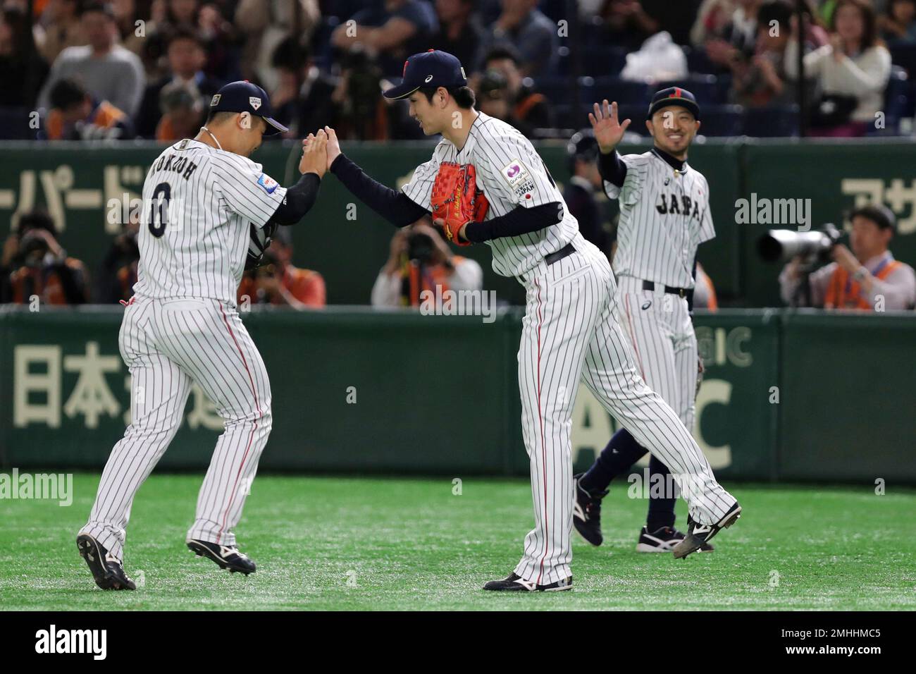 Japan's left fielder Kensuke Kondo (8) is welcomed by pitcher Rei Takahashi, center, and second ...