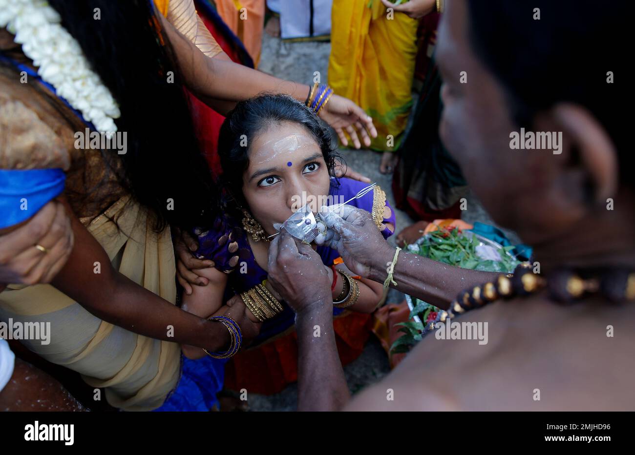 A Hindu priest pierces the cheeks of a devotee during Esala Poya Day at ...