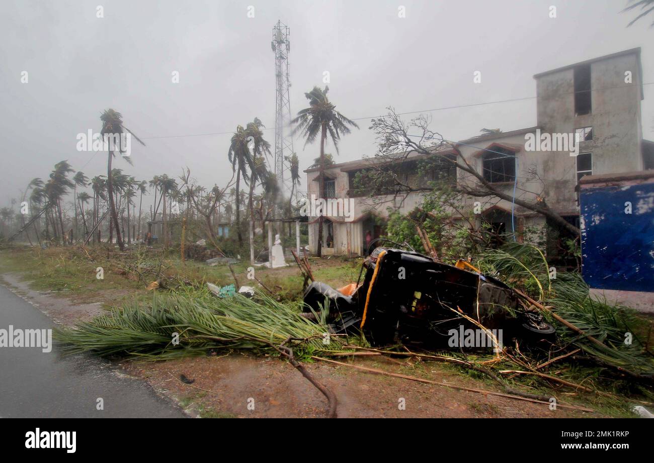 An auto-rickshaw and uprooted tress lie along a road in Puri district ...