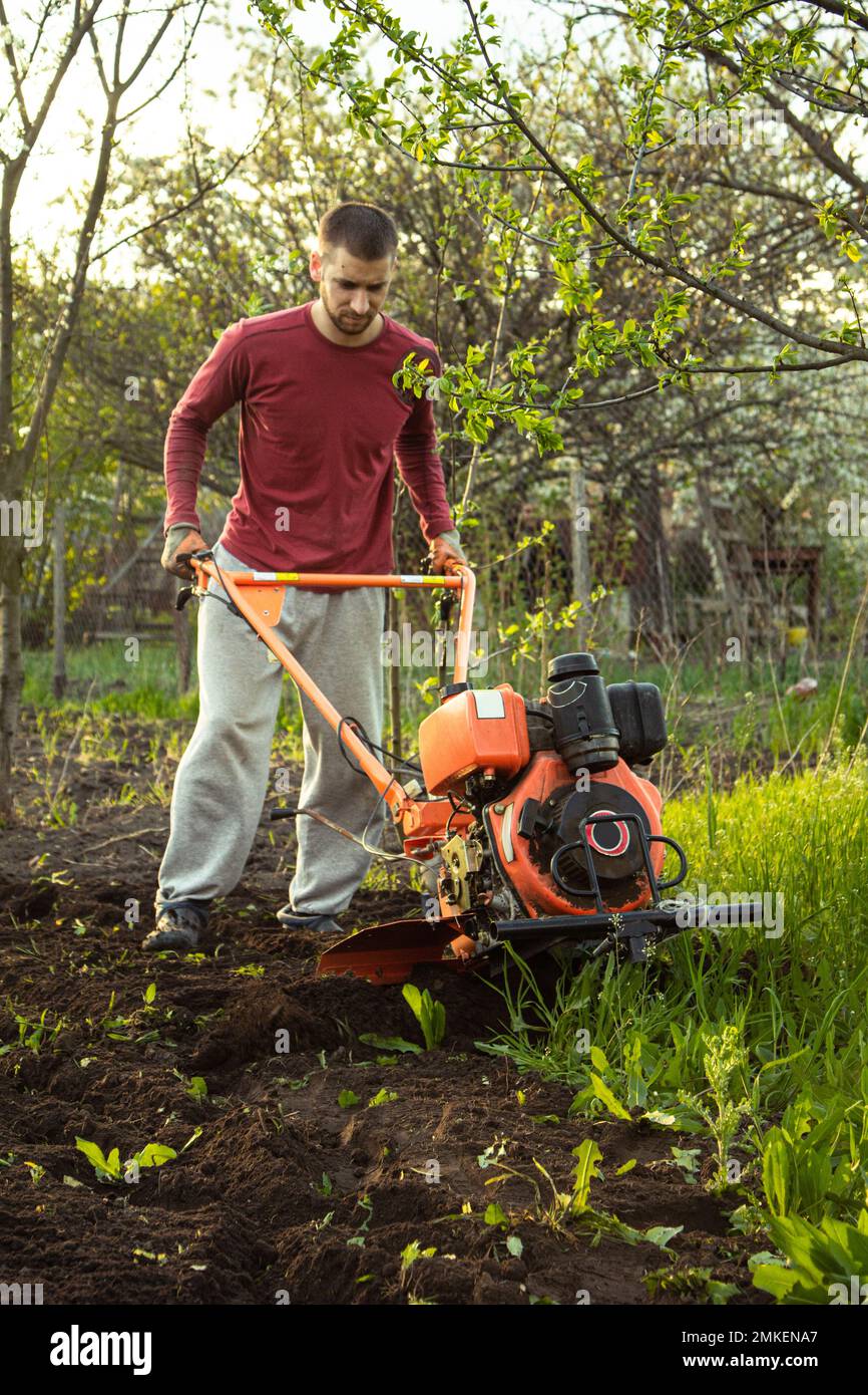 Un fermier travaille dans le champ, labourant la terre avec une charrue ...