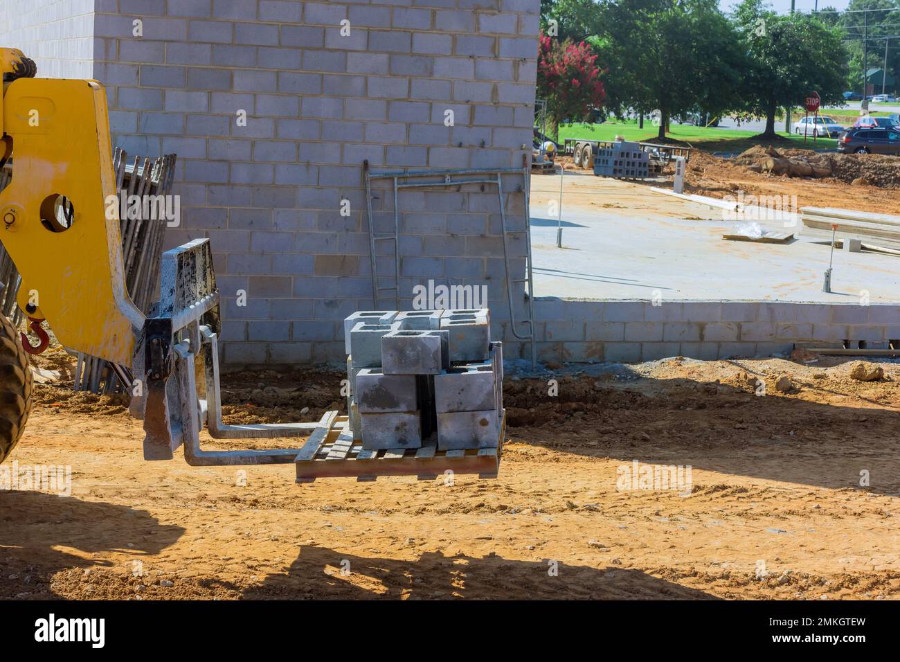 Les blocs de ciment sont déplacés par le chariot élévateur à flèche pour placer le mur de la ...