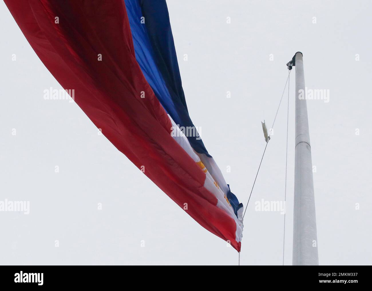 A Philippine flag is partly torn while being raised during flag-raising ...