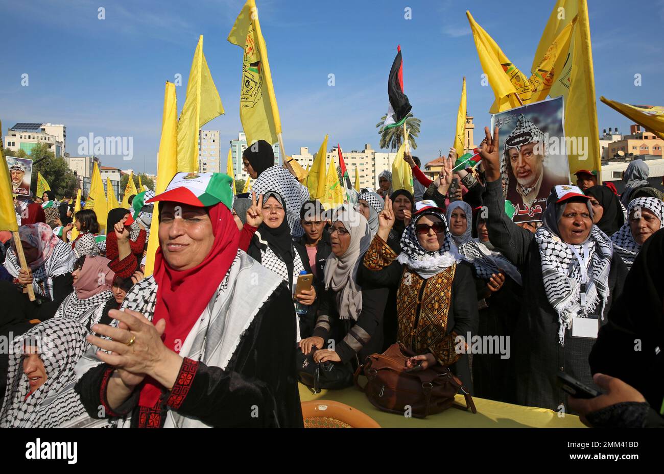 Palestinians celebrate while waving yellow Fatah flags and a picture of ...