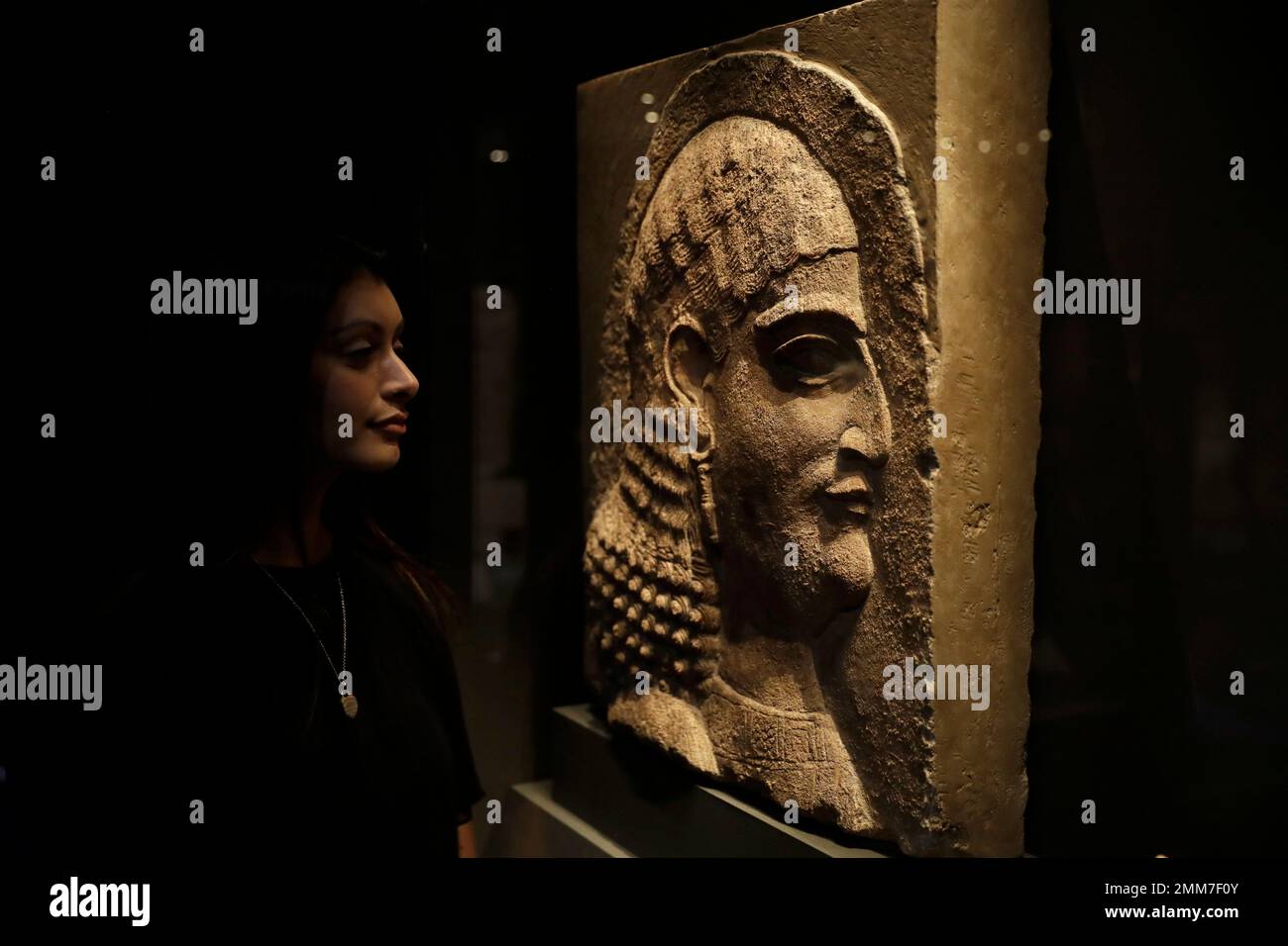 A British Museum staff member poses for photographers next to a relief ...
