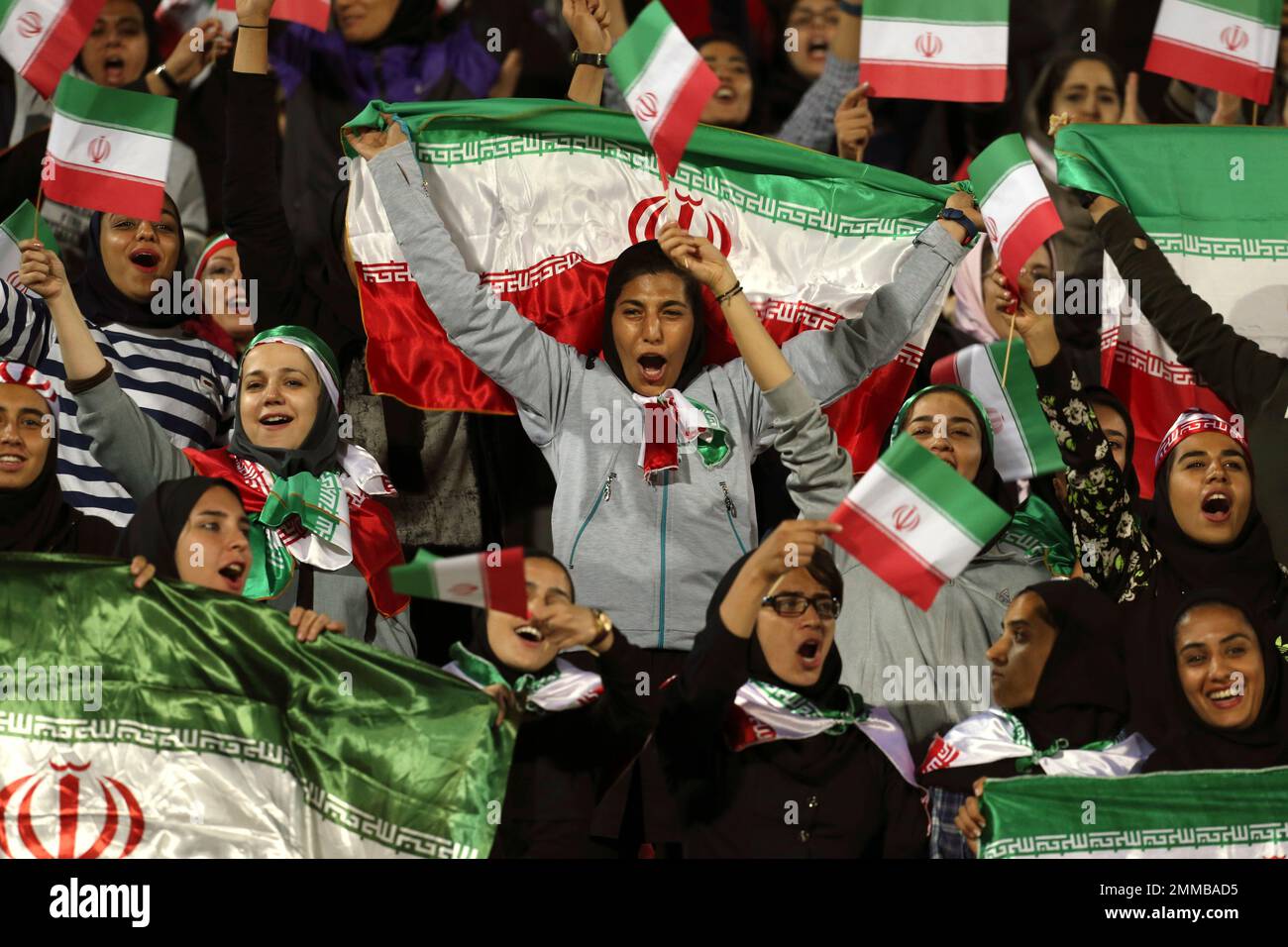 Female Iranian spectators cheer as they wave their country's flag ...