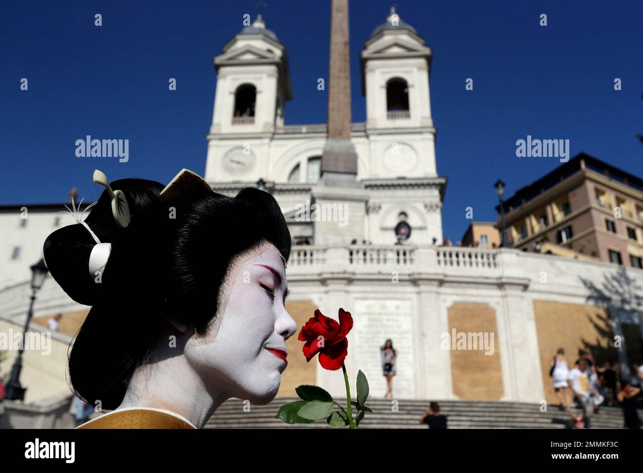 Geisha Asaka, sniffs a red rose as she poses for photographers at the ...