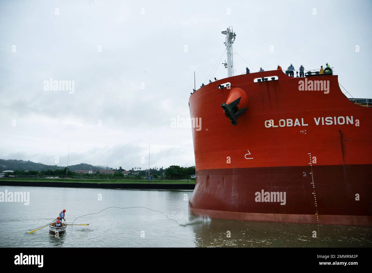 Two Panama Canal workers paddle in their small boat to catch ropes from ...