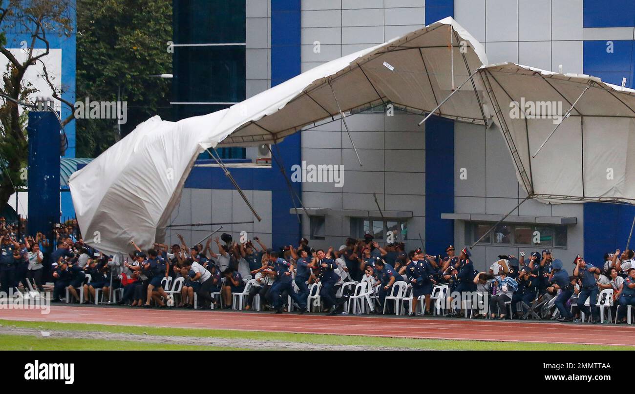 Philippine National Police officers and employees react as their tent ...