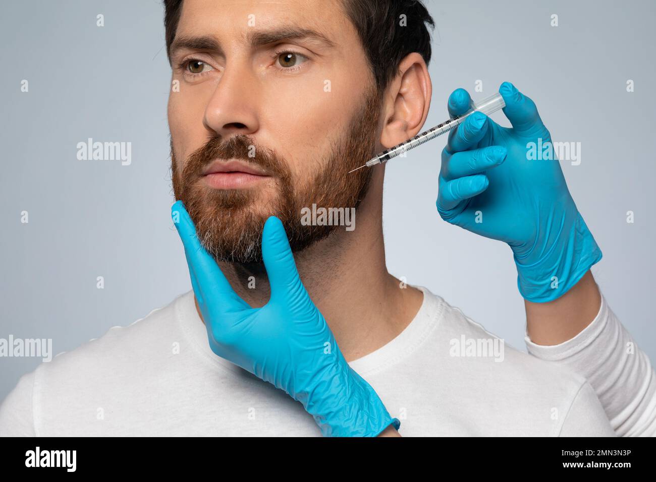 Homme barbu se faire une injection de beauté, les mains du cosmétologue ...