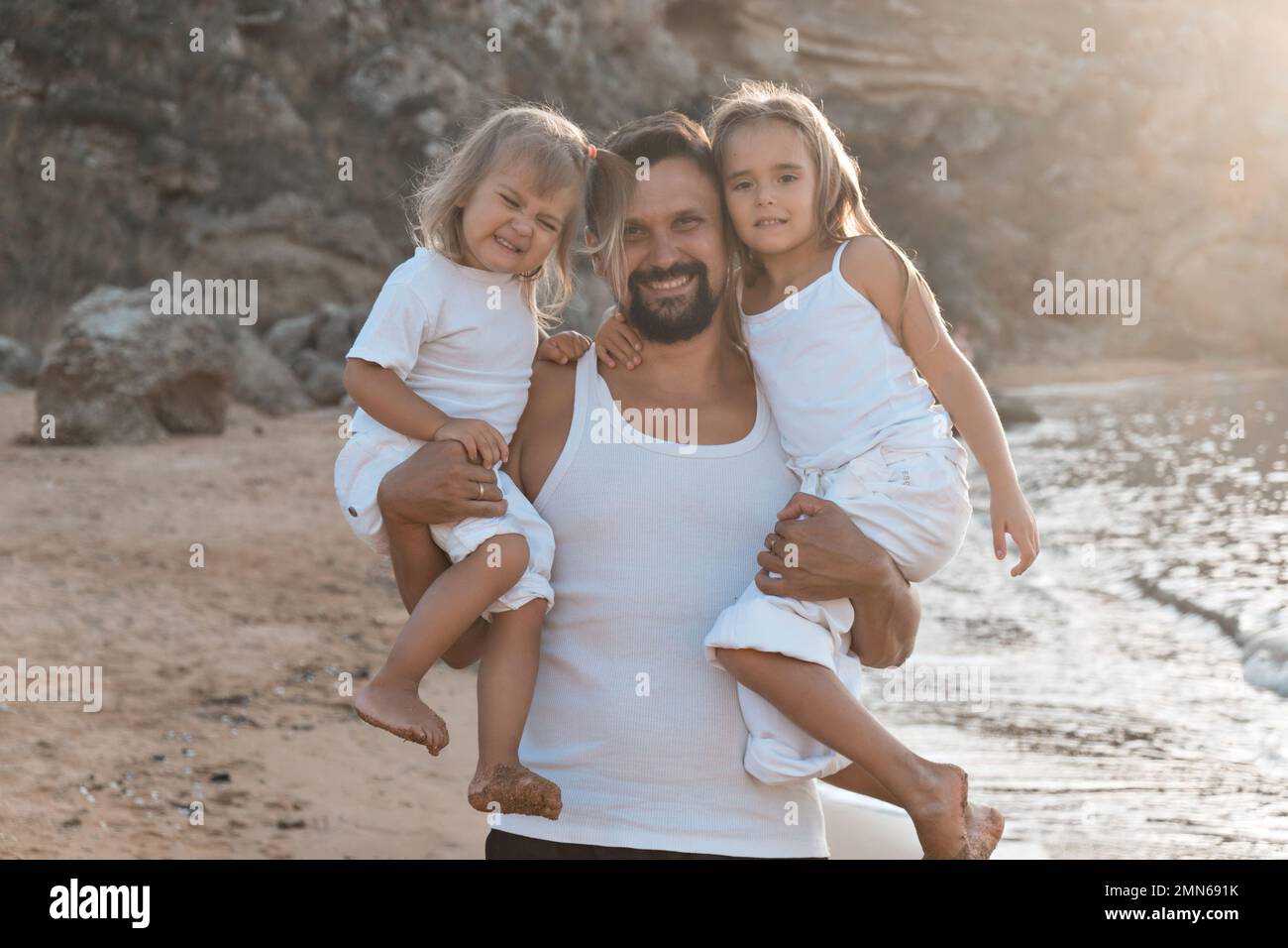 L'amour et le soin de papa. Le père tient deux filles dans ses bras, sa ...
