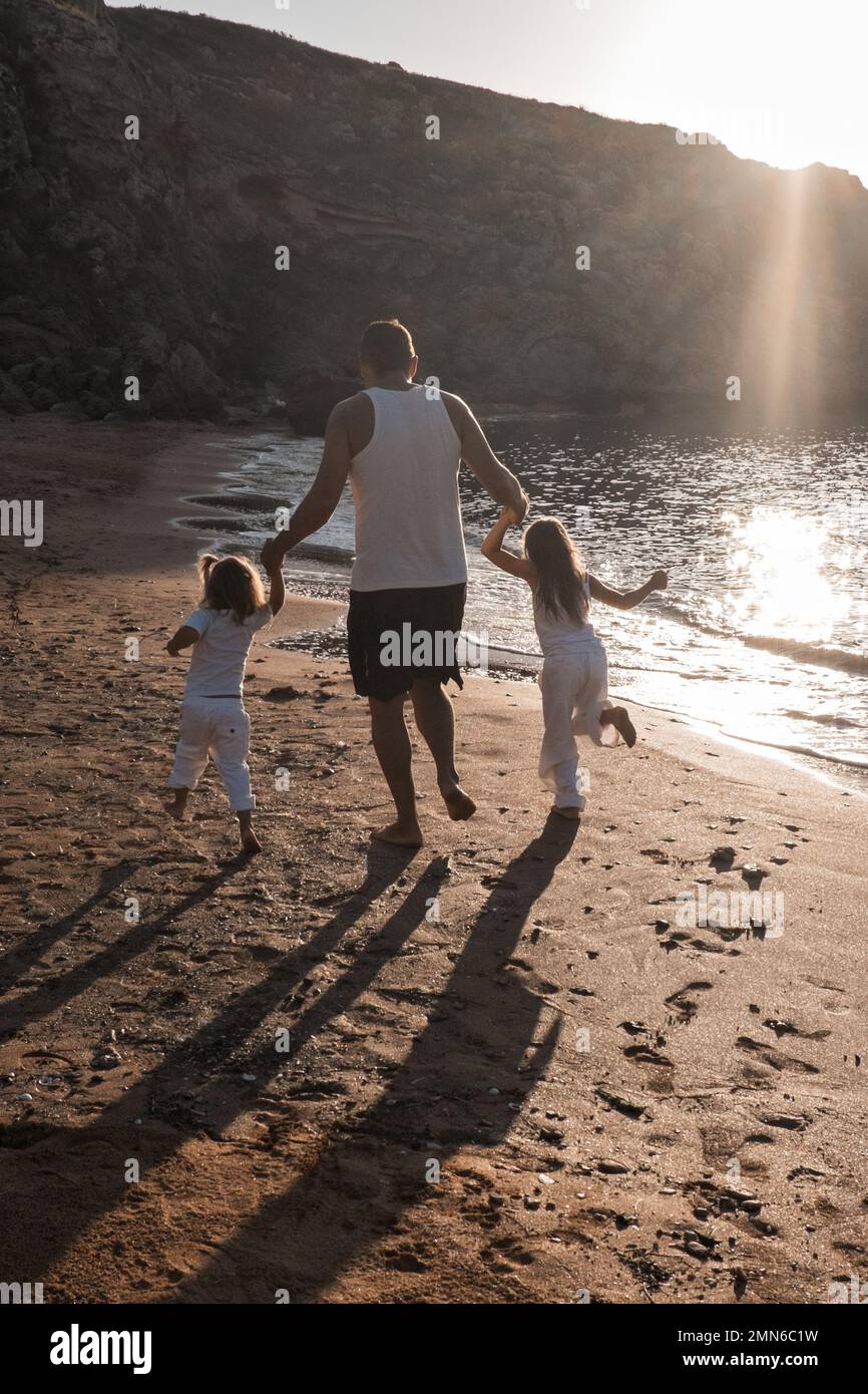 L'amour et le soin de papa. Le père tient deux filles dans ses bras, sa ...