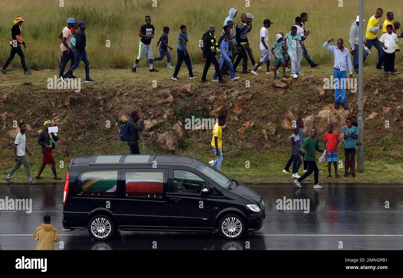 People follow the hearse carrying the coffin of anti-apartheid activist ...