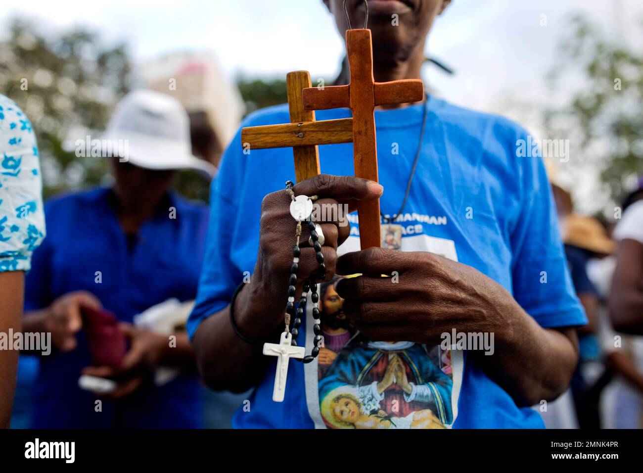 A woman holds crosses and a rosary as she prays at the first station of ...