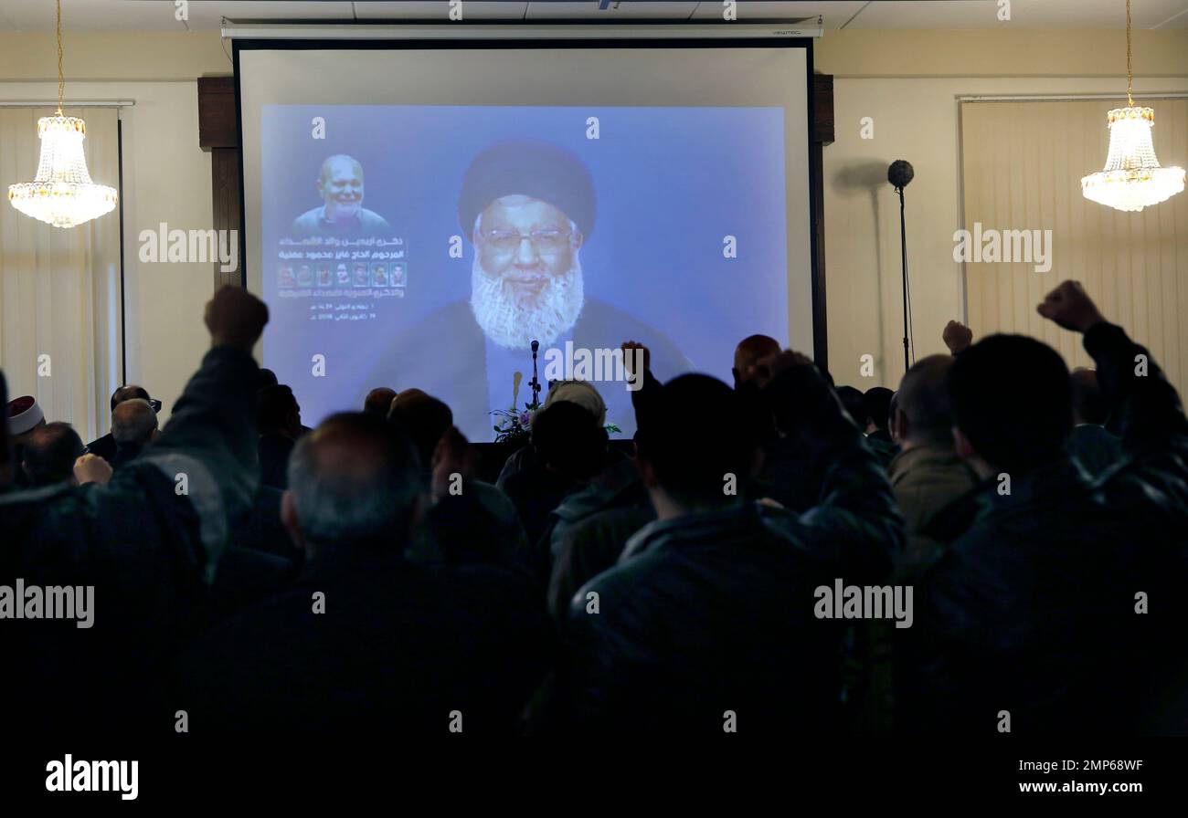 Hezbollah supporters raise their fists and cheer as they listen to a ...